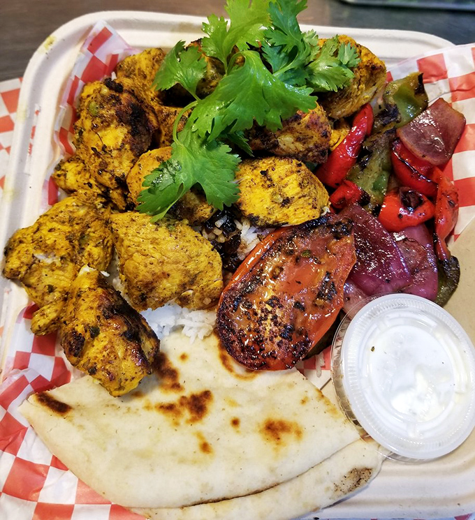 Sunshine on a plate! Saffron-kissed chicken kabob nestled on fragrant rice with grilled vegetables and warm pita &ndash; a vacation for your taste buds.