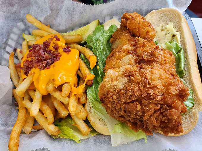 A chicken sandwich that requires both hands and possibly a building permit. The cheese-covered fries with bacon bits are performing backup vocals.