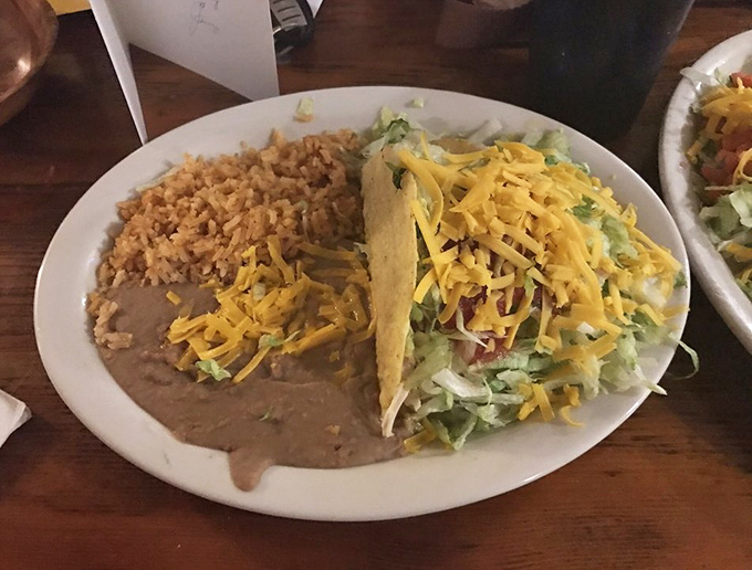 A perfect harmony of textures: crispy taco shell, fluffy rice, velvety beans. This isn't just lunch&mdash;it's a symphony orchestra conducted by someone's abuela.