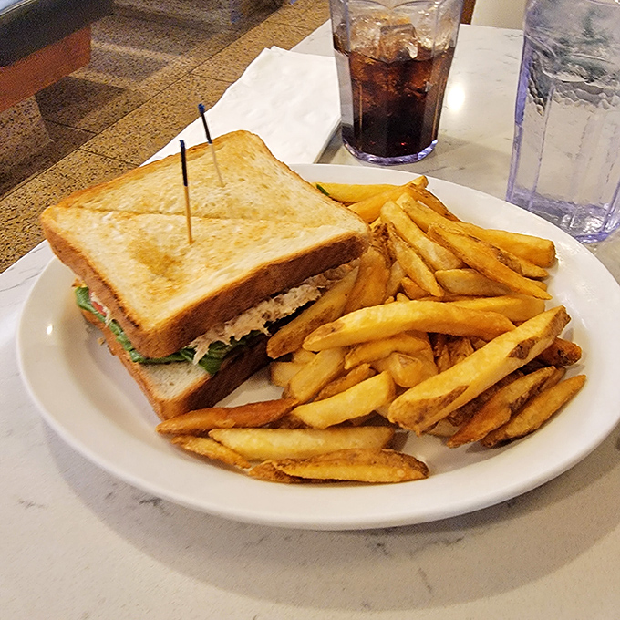 The club sandwich: America's most reliable lunch companion, flanked by an honor guard of golden fries standing at delicious attention.