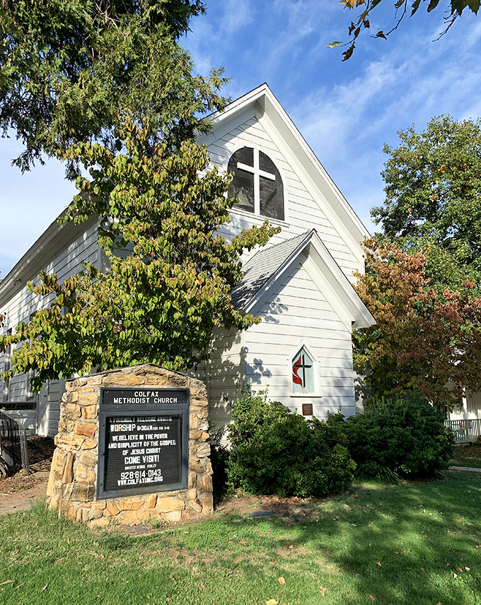 This picturesque Methodist church could star in a Hallmark movie, its white steeple reaching skyward amid autumn-kissed trees.