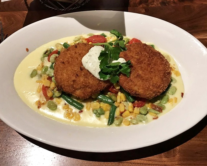These aren't just crab cakes; they're discs of seafood perfection resting on a summer garden of corn and vegetables bathed in sunshine-yellow sauce.