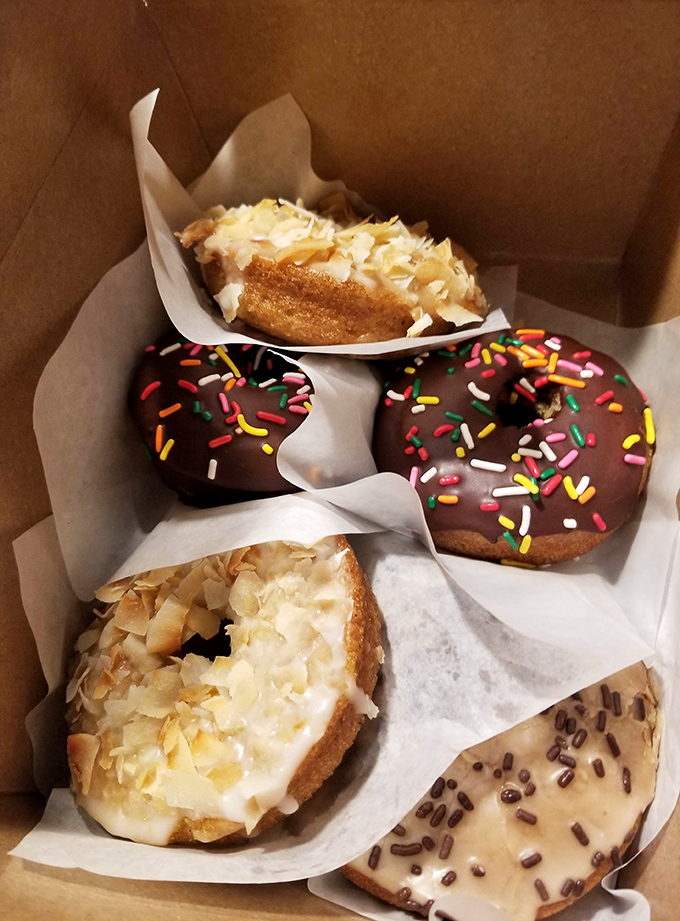 A bakery box that doubles as a treasure chest. Those chocolate-dipped donuts with rainbow sprinkles are childhood joy in edible form.