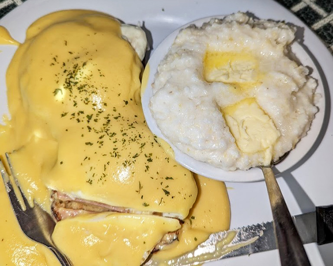 Hollandaise sauce cascading over eggs Benedict like a golden waterfall, with grits standing by for Southern moral support.