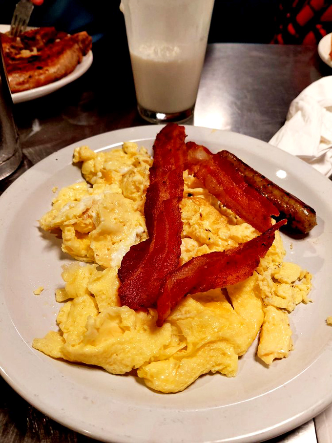 The breakfast trinity: perfectly scrambled eggs, bacon with the ideal crisp-to-chew ratio, and a glass of water patiently waiting its turn.