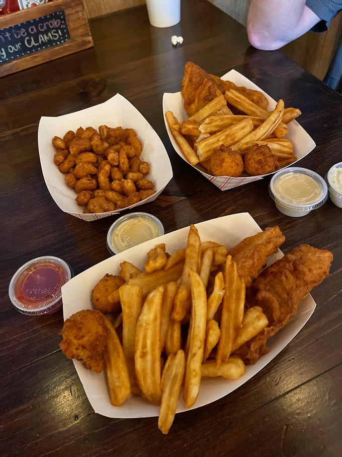 The holy trinity of fried goodness: fish, fries, and chicken, with dipping sauces standing by like loyal sidekicks ready for action.