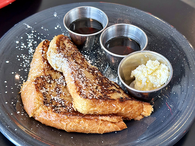 The legendary French toast arrives like breakfast royalty—golden-brown, dusted with powdered sugar, and accompanied by its loyal subjects: butter and syrup.