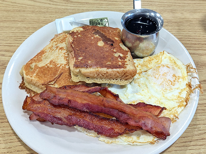The breakfast trinity: golden French toast, eggs with that perfect sunny-side up smile, and bacon crisped to that magical point between chewy and crunchy. 