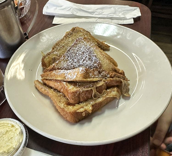French toast that's dressed up for the occasion, dusted with powdered sugar like it just walked through a delicious snowstorm.