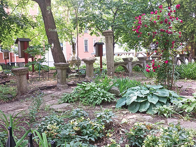 The garden features classical stone elements and lush plantings, offering a peaceful contrast to the imposing architecture of the main house.
