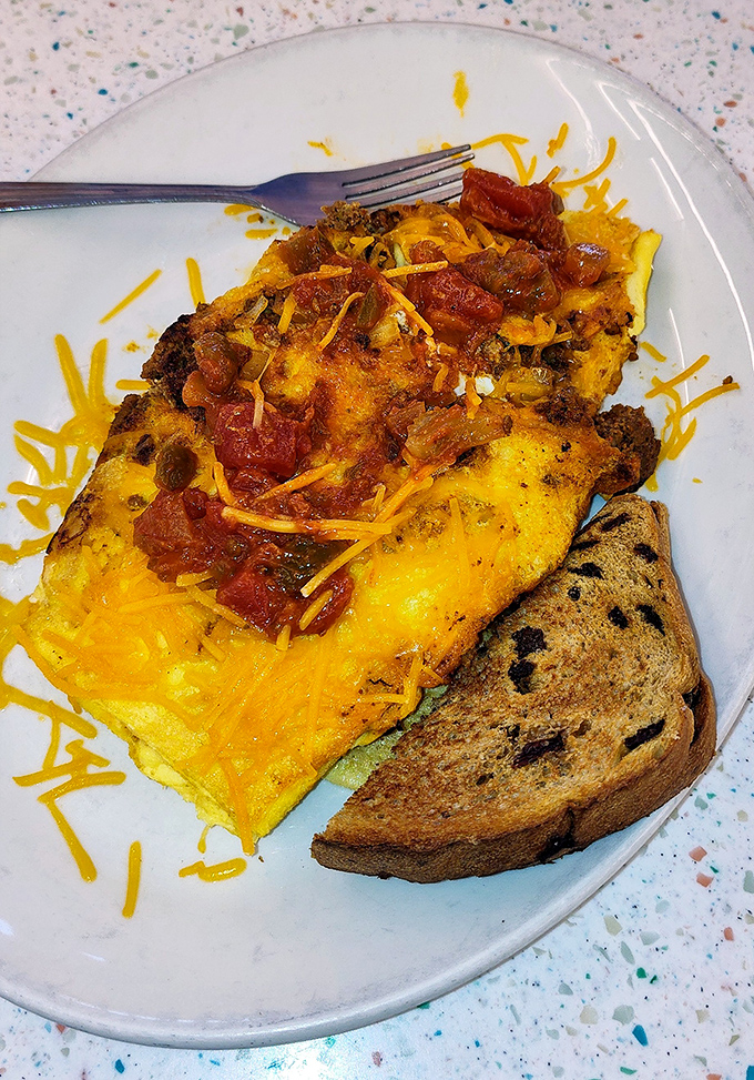 This omelet doesn't just contain ingredients; it tells a Mediterranean story with every cheese-draped, tomato-studded bite.