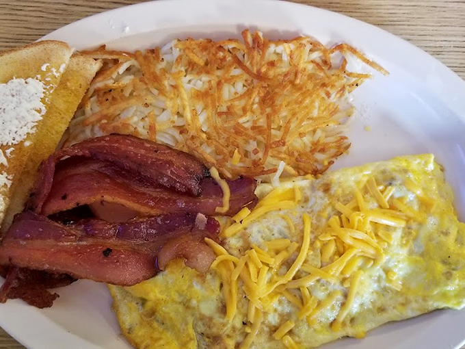 The breakfast trinity: perfectly folded omelet, crispy bacon, and hash browns with that ideal golden crust that makes you want to applaud the cook.