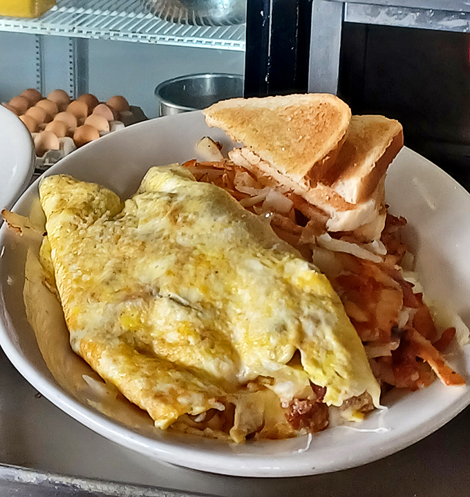 An omelet that doesn't just sit on hash browns but embraces them completely—the breakfast equivalent of a warm bear hug.