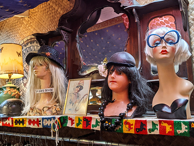 A trio of mannequin heads sporting vintage hats and wigs silently judge your fashion choices from their colorful perch.
