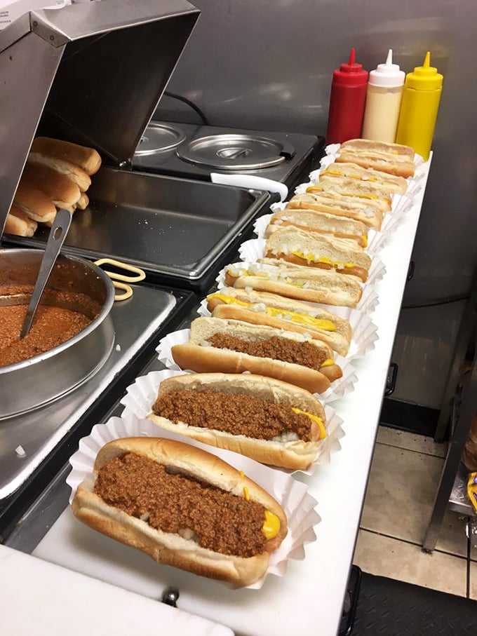 Assembly line of happiness—these chili dogs lined up like soldiers ready to battle hunger with mustard-yellow streaks of deliciousness.