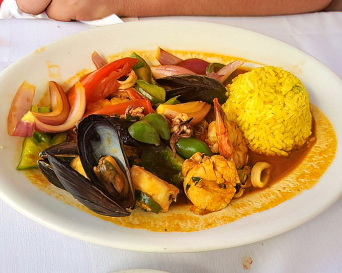 Mariscos Saltados brings the ocean to your plate with a colorful medley of seafood swimming in a vibrant sauce alongside perfectly cooked yellow rice.