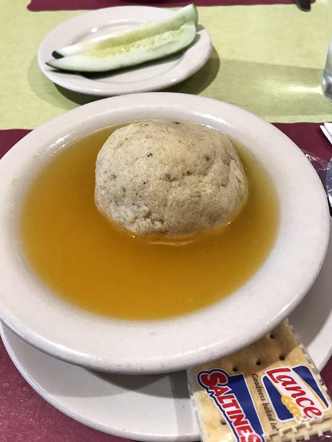 The matzo ball soup &ndash; where a perfect dumpling floats like the moon in a golden broth universe that could cure anything from colds to existential crises.