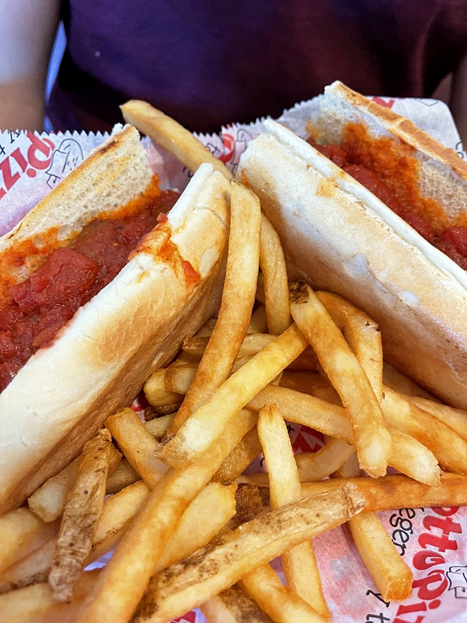 The humble meatball sub elevated to art form, with golden fries standing at attention like delicious potato soldiers.