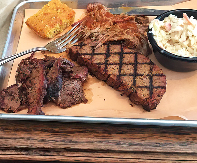 A BBQ sampler that showcases the holy trinity: ribs with perfect grill marks, tender brisket, and pulled pork, with cornbread and coleslaw for balance.