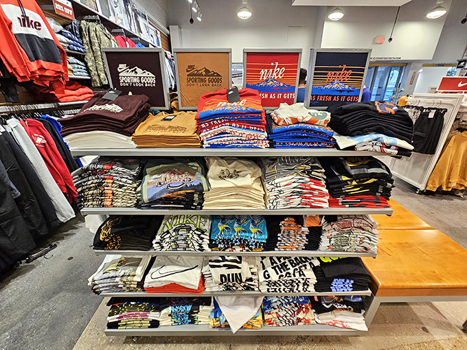 The Nike shrine where graphic tees are stacked with military precision, each one promising to make you look like you might actually use that gym membership.