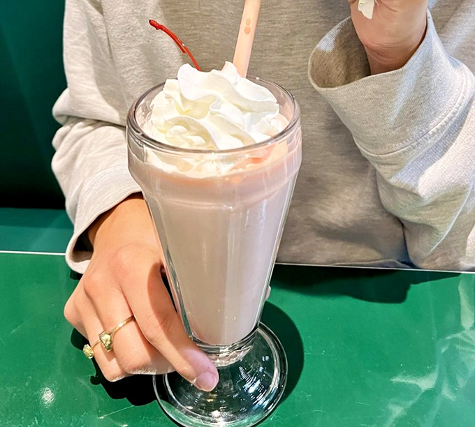 A proper milkshake served in its natural habitat&mdash;tall glass, metal mixing cup on standby, and whipped cream defying gravity.