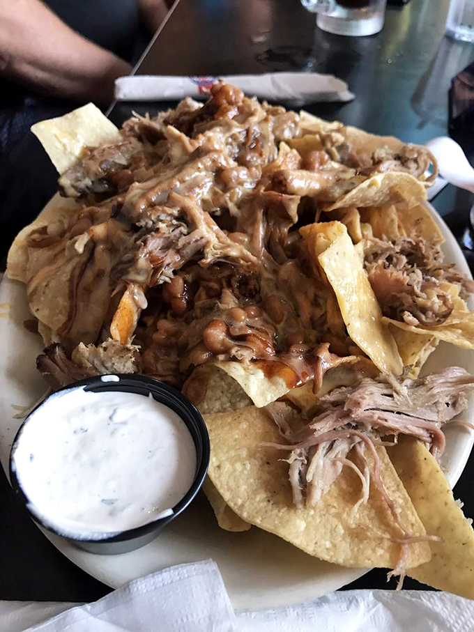 Pulled pork nachos that don't mess around—a mountain of chips buried under tender meat, with that signature root beer BBQ sauce adding sweet-smoky notes.