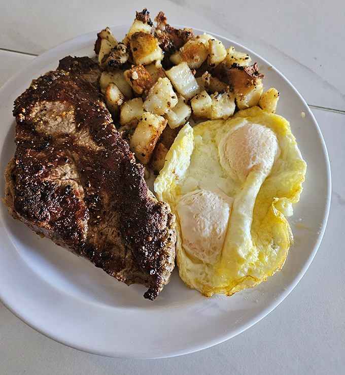 A New York steak cooked exactly how you want it, alongside eggs and home fries&mdash;proof that sometimes the simplest combinations are the most satisfying.