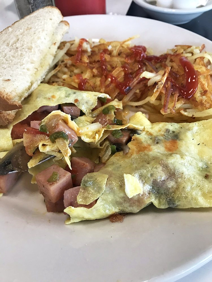 An omelet that's seen things, stuffed with enough fillings to qualify as a small apartment. Those hash browns are the perfect neighbors.