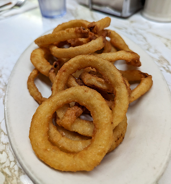 Golden, crispy onion rings stacked like delicious life preservers, ready to rescue you from the sea of ordinary fast food options.