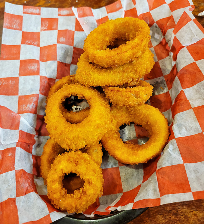 Golden onion rings that crunch like autumn leaves, served in that classic red-checkered paper that signals good things are about to happen.