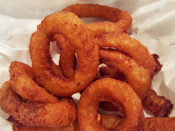 Onion rings wearing beer-battered jackets so crisp they practically snap, forming perfect golden halos that angels would fight over.