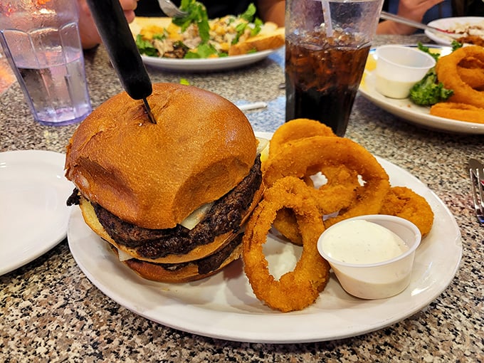 This burger stands tall like Idaho's mountains, flanked by onion rings so perfectly golden they deserve their own trophy case.