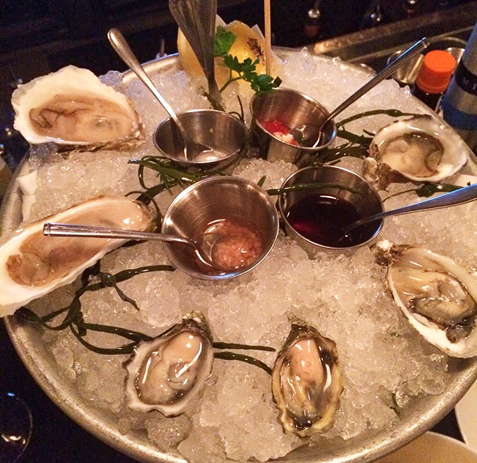 Oysters presented like jewels on a bed of ice. Those tiny cups of mignonette and cocktail sauce are the supporting actors in this briny drama.