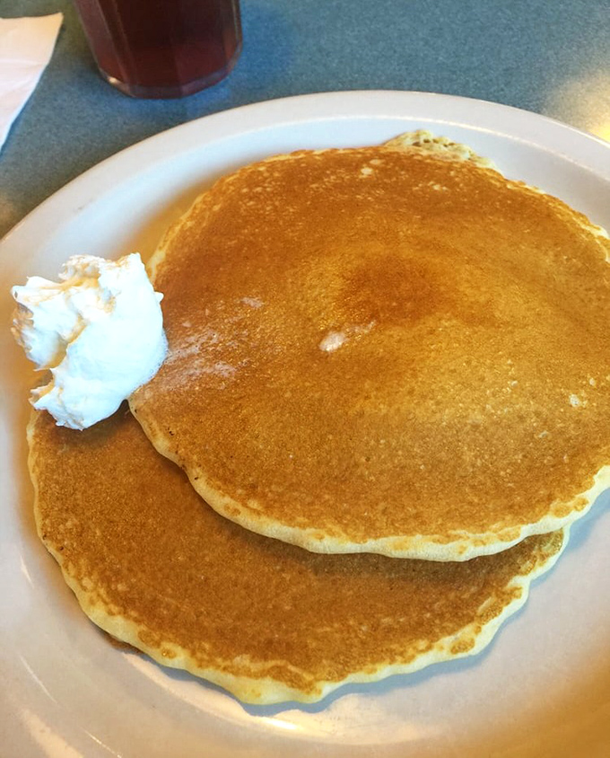 Pancakes stacked higher than your weekend expectations, with the kind of golden-brown perfection that makes maple syrup weep with joy.