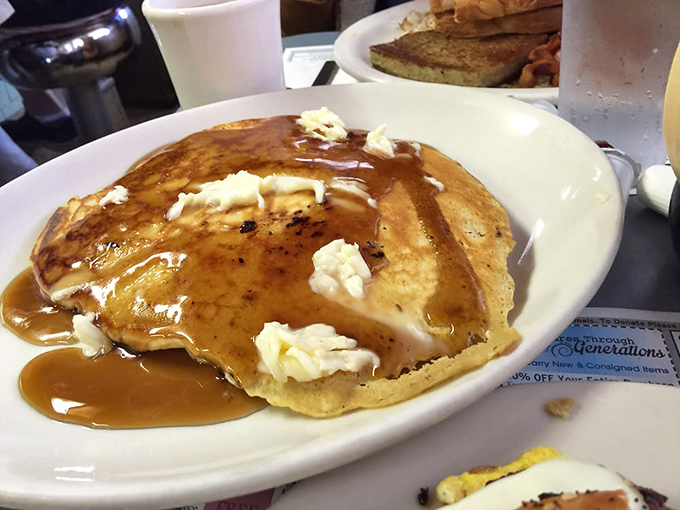 A pancake so perfectly golden it belongs in Fort Knox, with butter melting like a slow-motion food commercial. Maple syrup never had it so good.