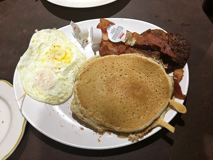 The classic American breakfast trinity: golden pancake, perfectly fried eggs, and bacon that's achieved that magical balance between crisp and chewy.