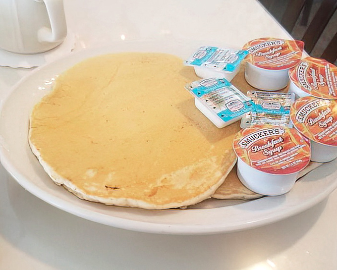 Pancakes so perfectly golden they look like they've been sunbathing, with syrup packets standing by like eager lifeguards ready to dive in.