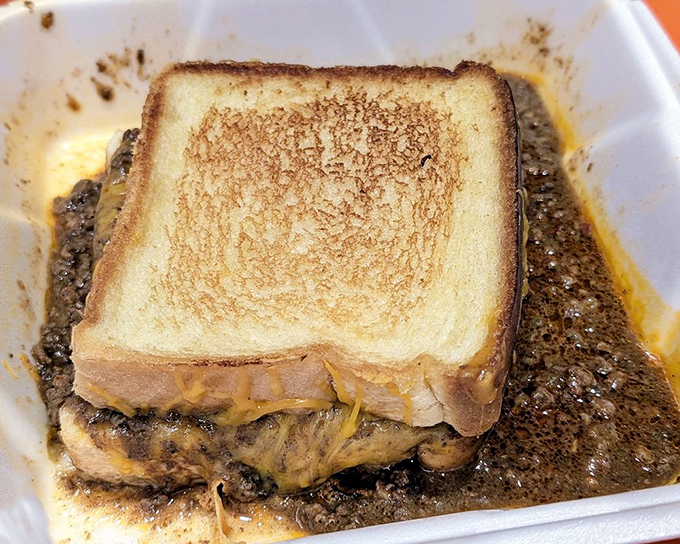 This patty melt has clearly been baptized in chili—a delicious mess that requires strategic eating and zero concern for shirt stains.