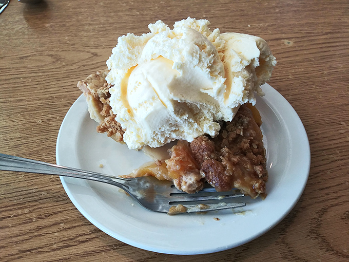 Pie à la mode that proves heaven exists on earth—warm fruit filling, crumbly topping, and ice cream melting into all the right places.