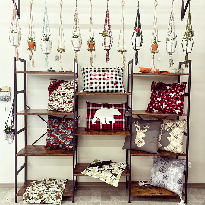 Plant parenthood meets textile artistry in this display where macram&eacute; hangers and buffalo plaid pillows create the perfect rustic-modern marriage.