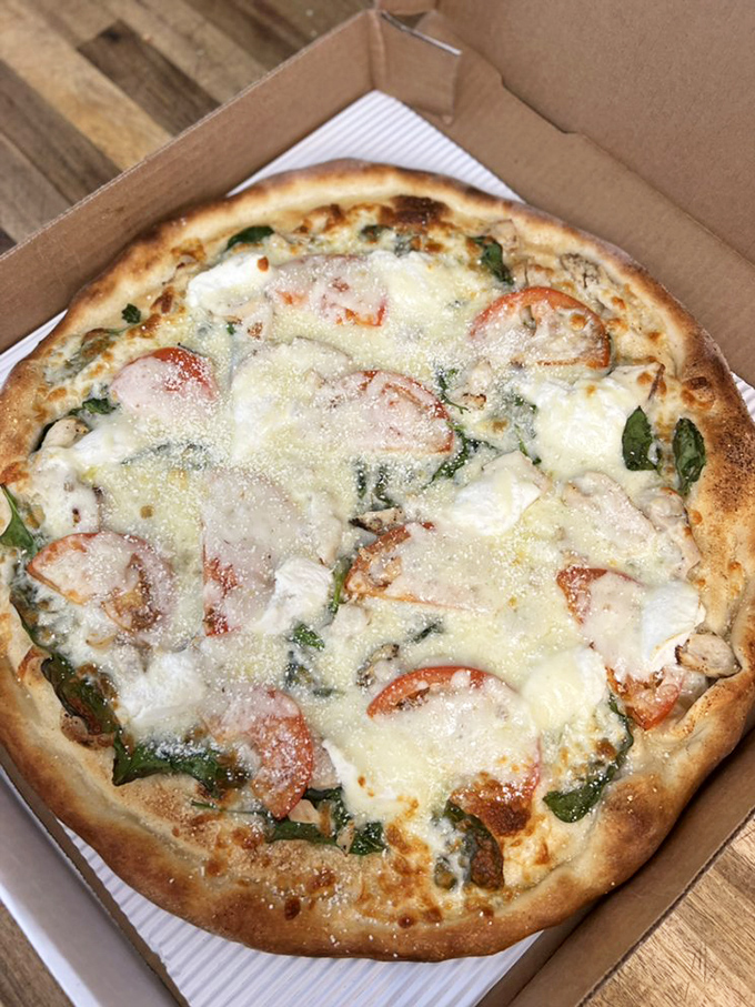 Fresh tomatoes and spinach make this white pizza feel almost virtuous. Almost. The cheese pulls say otherwise.