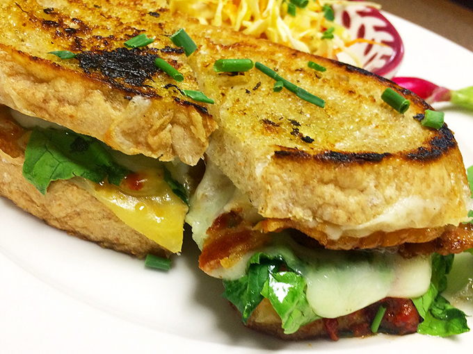 Melted cheese oozes between perfectly grilled bread, with fresh greens adding color and crunch. Comfort food that graduated with honors.