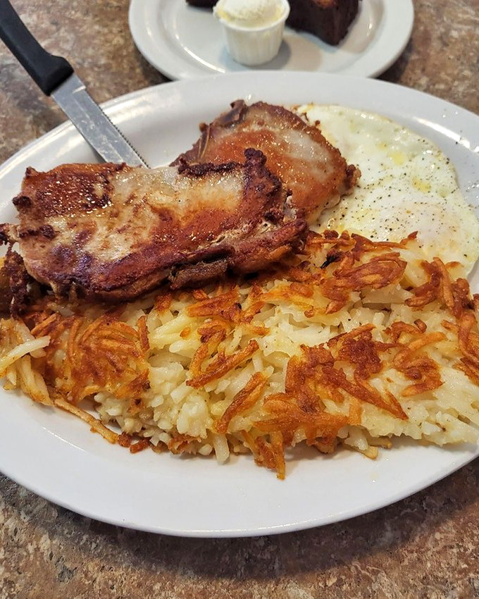 The holy trinity of breakfast perfection: crispy pork chops, sunny-side eggs, and hash browns crisped to golden perfection. Morning salvation on a plate.