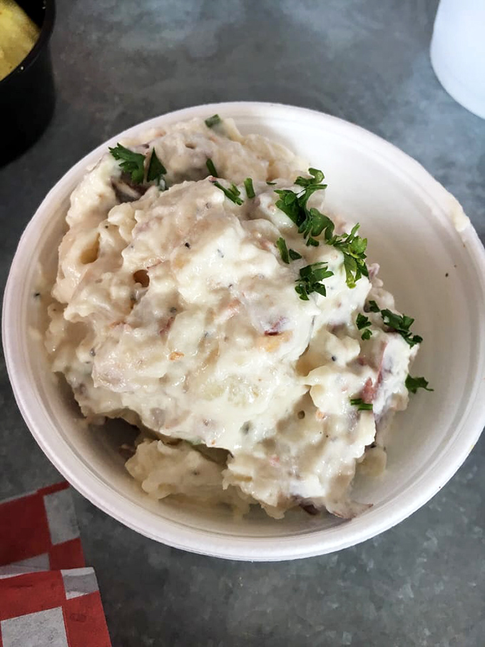 Creamy potato salad with fresh herbs stands ready for its noble purpose—cooling your palate between bites of Nashville's famous fiery fowl.