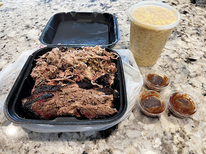 A takeout container of BBQ heaven&mdash;brisket and pulled pork with sauce on the side. The kind of meal that makes you grateful for opposable thumbs.