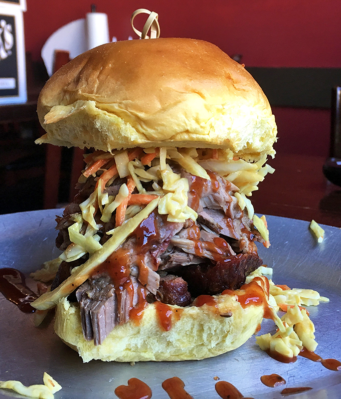 Architecture of deliciousness: pulled pork piled high, crowned with slaw, and sauced just right. A skyscraper of flavor worth climbing.