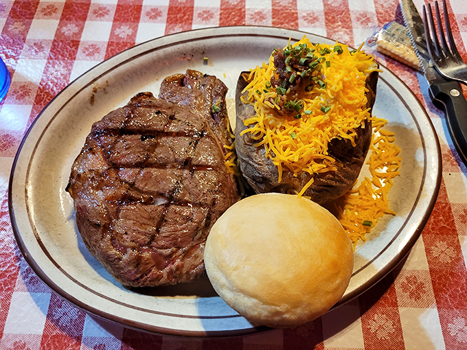 A ribeye cooked with the reverence it deserves, accompanied by a loaded baked potato and roll that know their supporting roles perfectly.