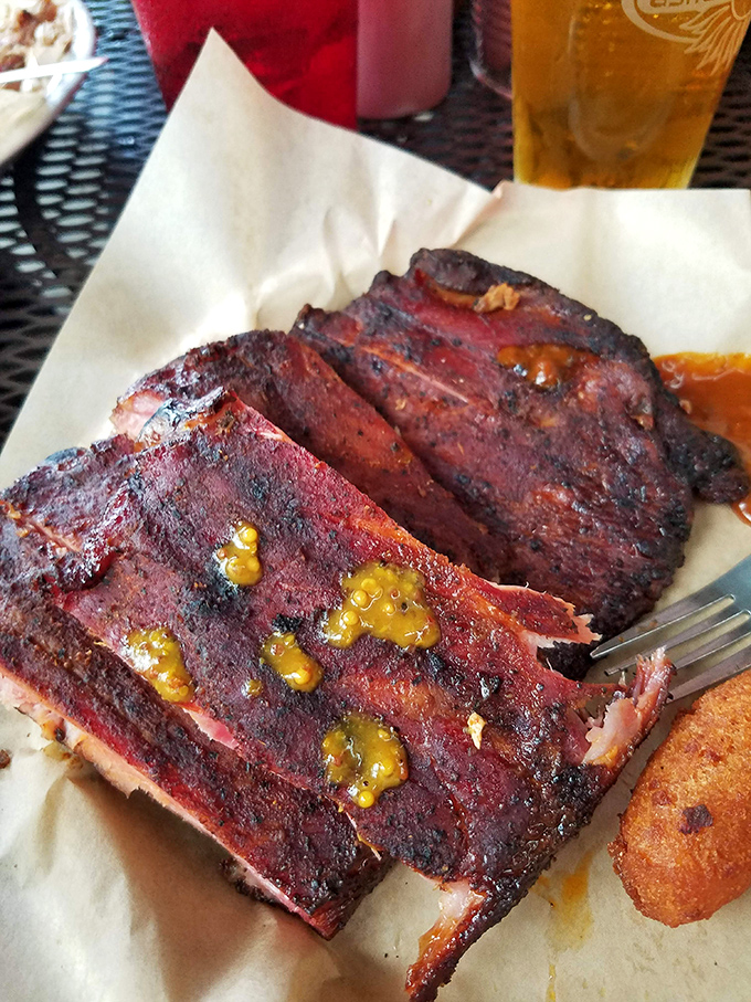 Ribs with a bark so perfect they should be in a barbecue museum, glistening with sauce that whispers, "Napkins are for quitters."