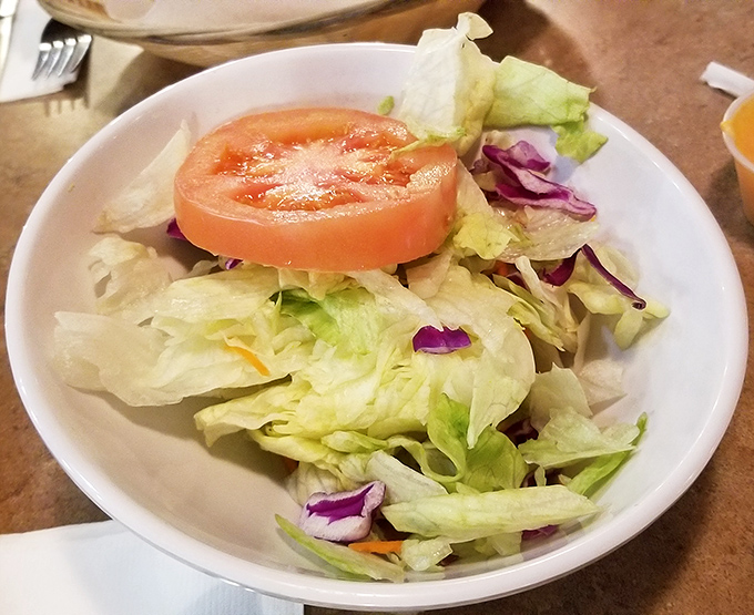 The salad exists as a symbolic gesture toward nutrition, a crisp, colorful island in a sea of delicious barbecue indulgence.