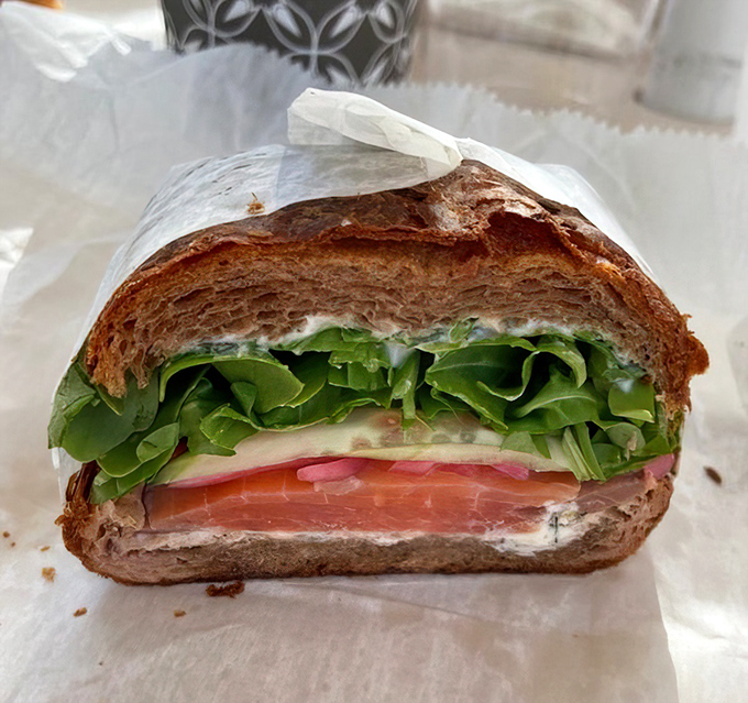 Not your sad desk lunch—this salmon sandwich elevates the humble concept with architectural precision and ingredients that actually taste like themselves.